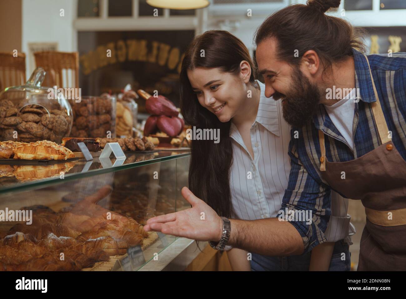 Young beautiful woman buying delicious freshly baked pastry at local ...