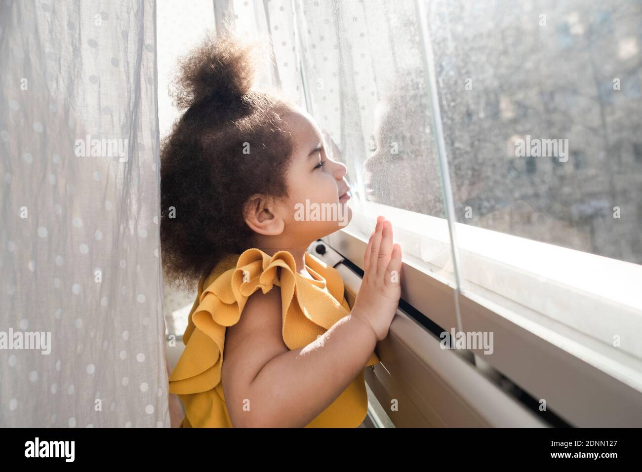 Girl looking through window Stock Photo - Alamy