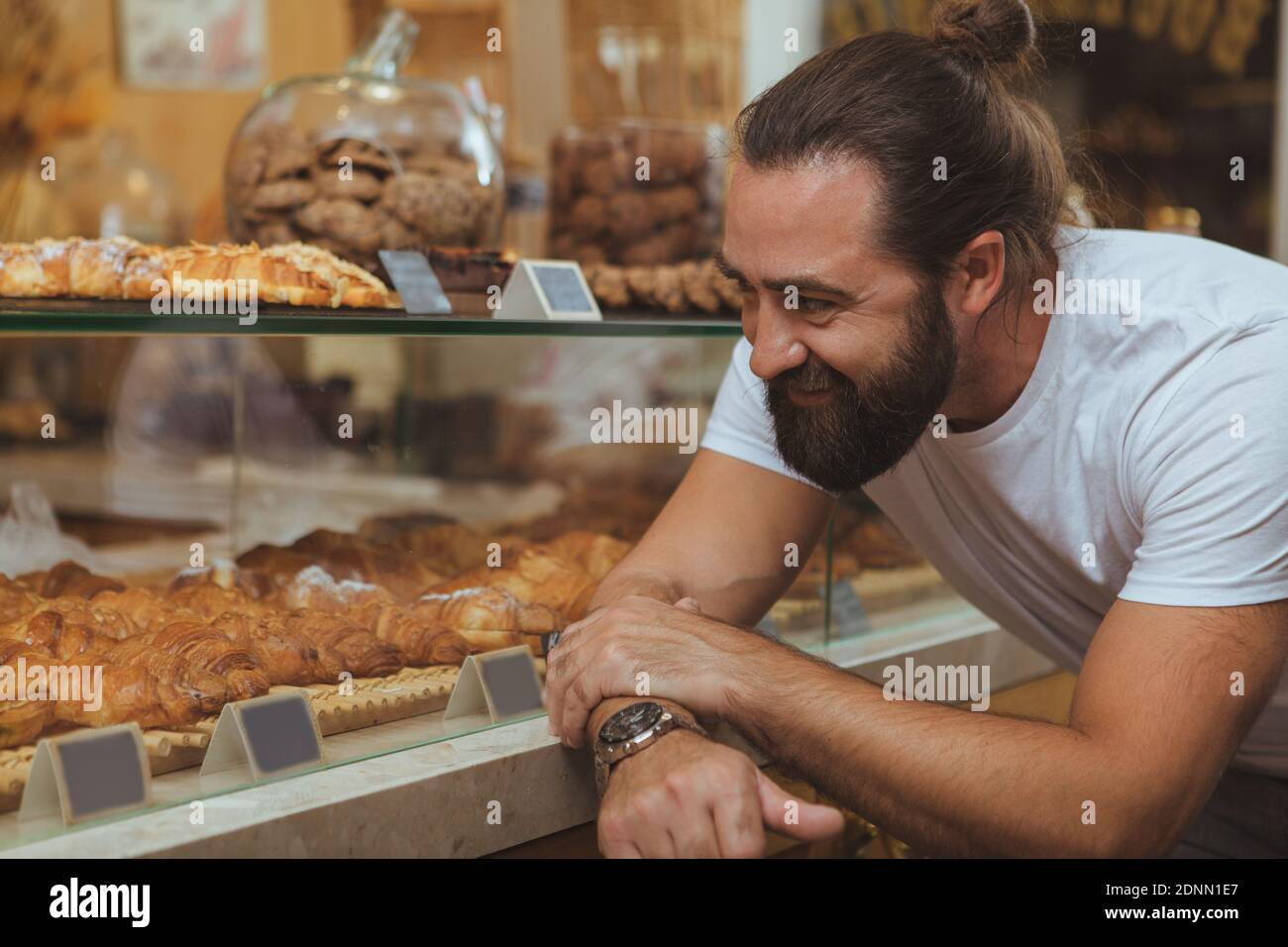 Long haired handsome mature man choosing delicious desserts from the ...