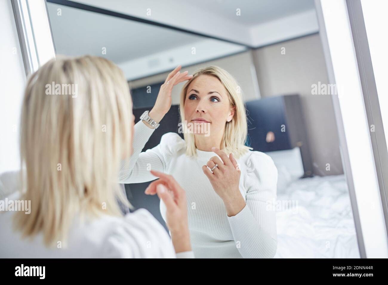 Woman looking in mirror Stock Photo - Alamy
