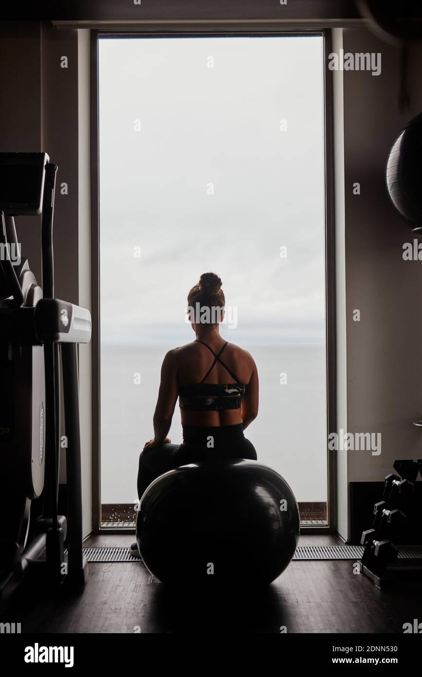 Woman on fitness ball looking through window Stock Photo - Alamy