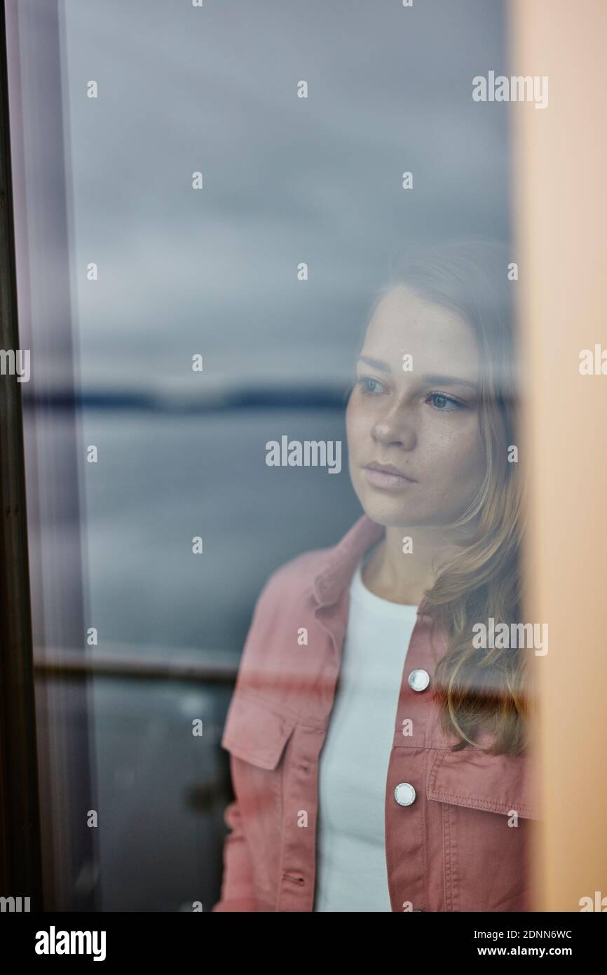 Woman looking through window Stock Photo - Alamy