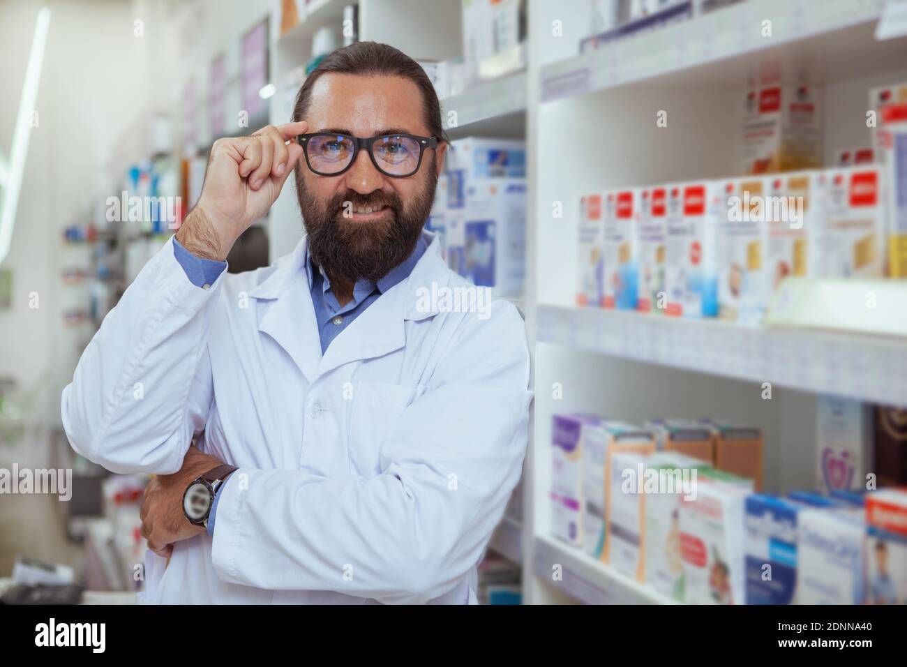 Friendly mature male pharmacist smiling to the camera, putting on his ...