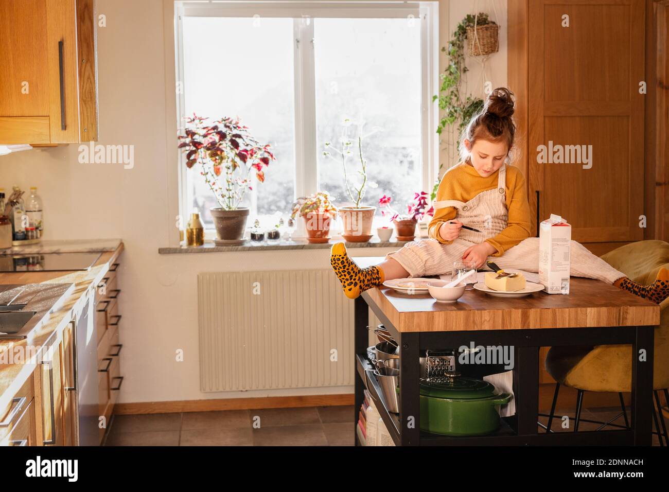 Girl sitting on table with cooking ingredients Stock Photo - Alamy