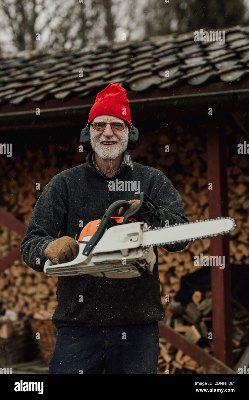 Senior man holding chainsaw Stock Photo - Alamy