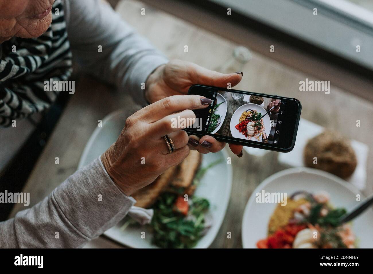 Hands with cell phone photographing food on table Stock Photo - Alamy