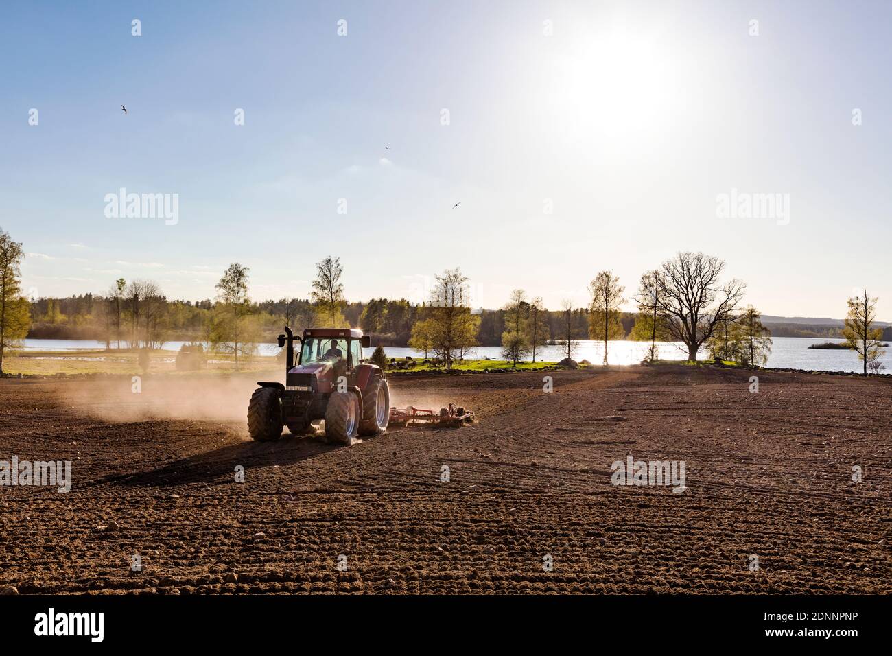 Tractor harrowing field Stock Photo - Alamy