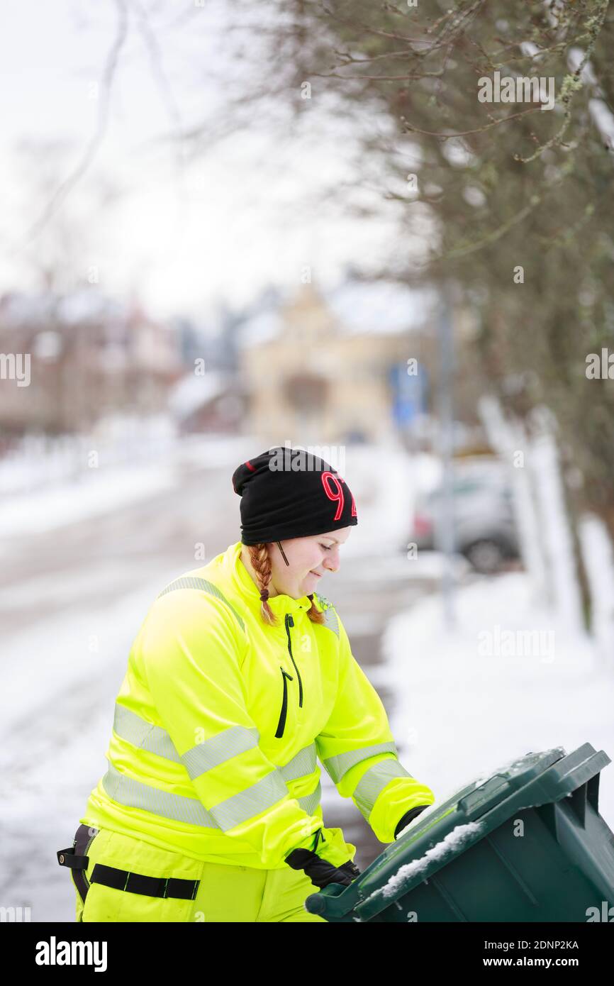 Woman pushing dustbin Stock Photo - Alamy