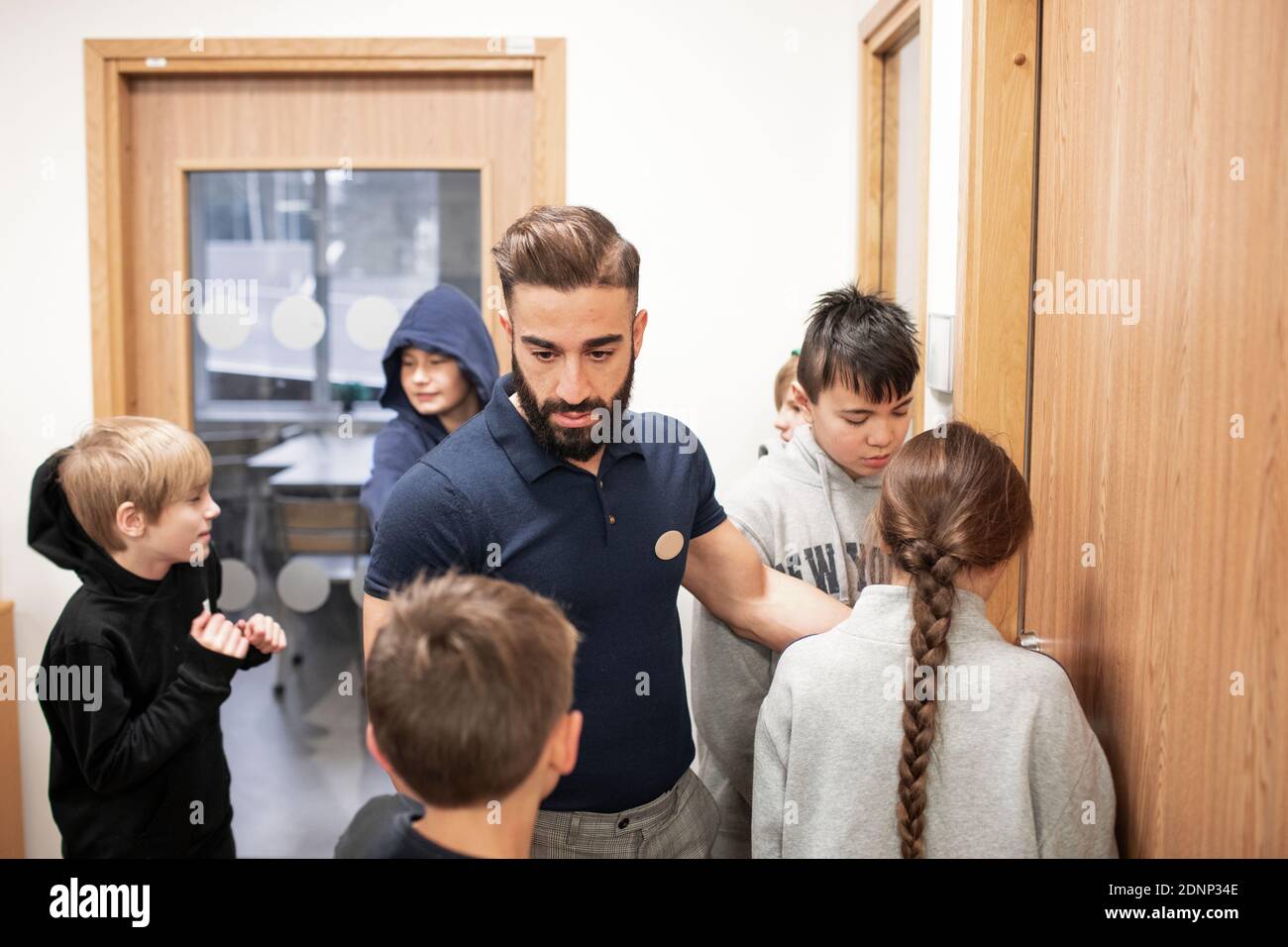 Teacher talking to children at school corridor Stock Photo - Alamy
