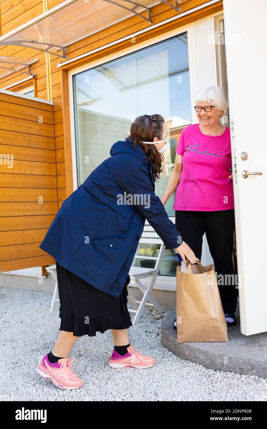 Woman delivering shopping to senior woman Stock Photo - Alamy