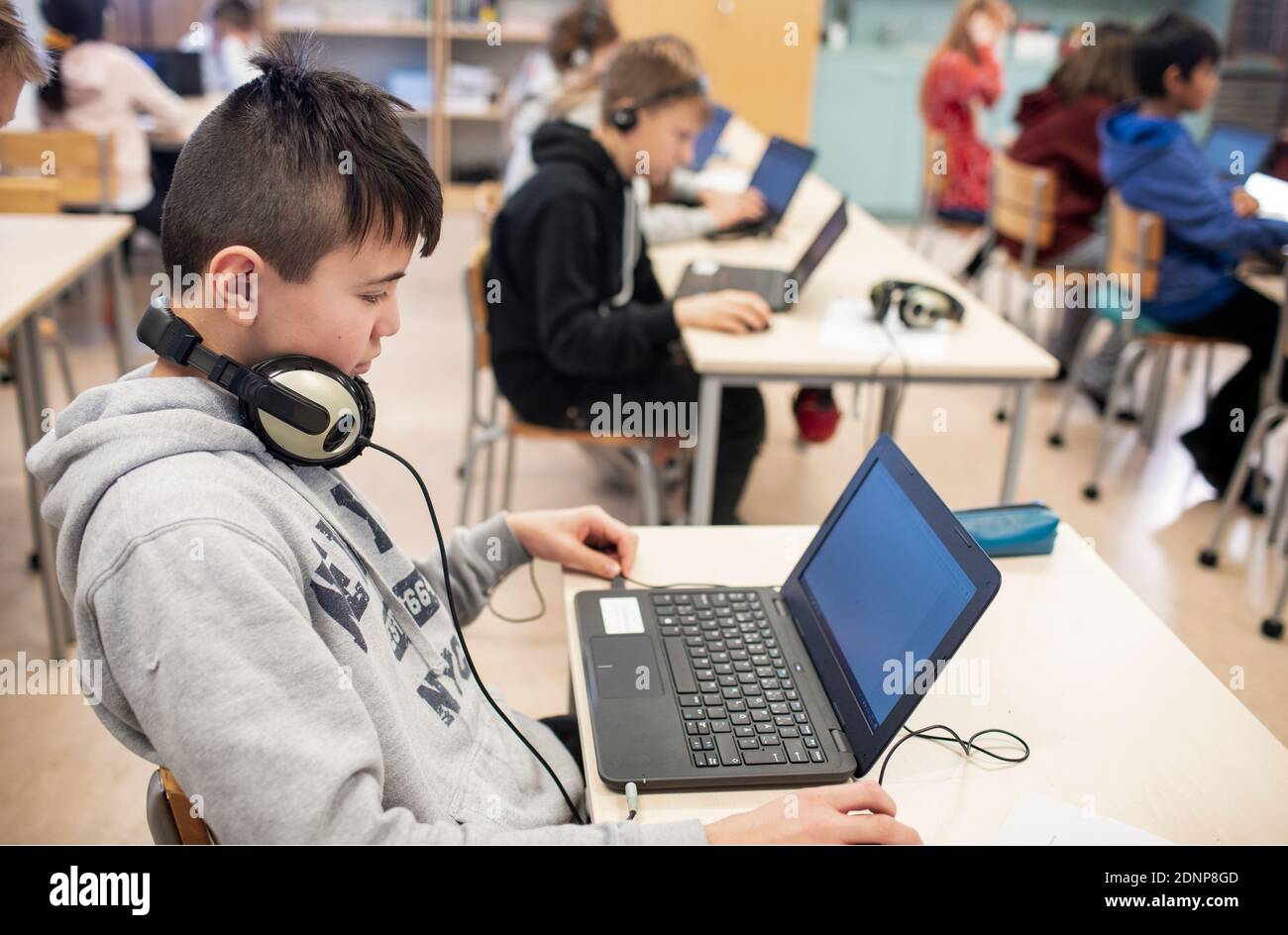 Boy in classroom using laptop Stock Photo - Alamy