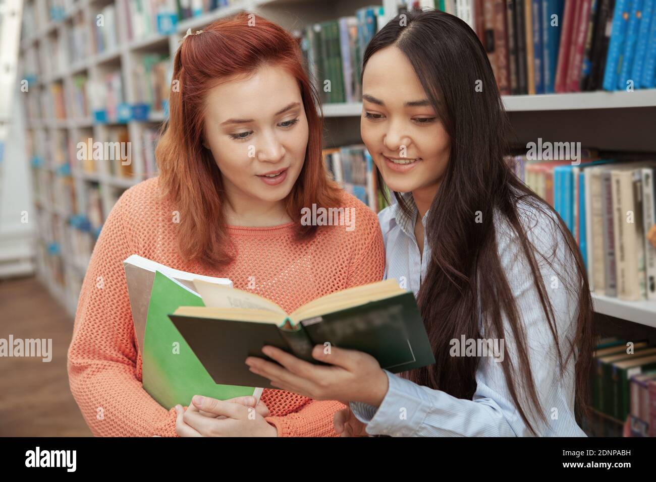 Lovely female college friends enjoying studying at the library. Female ...