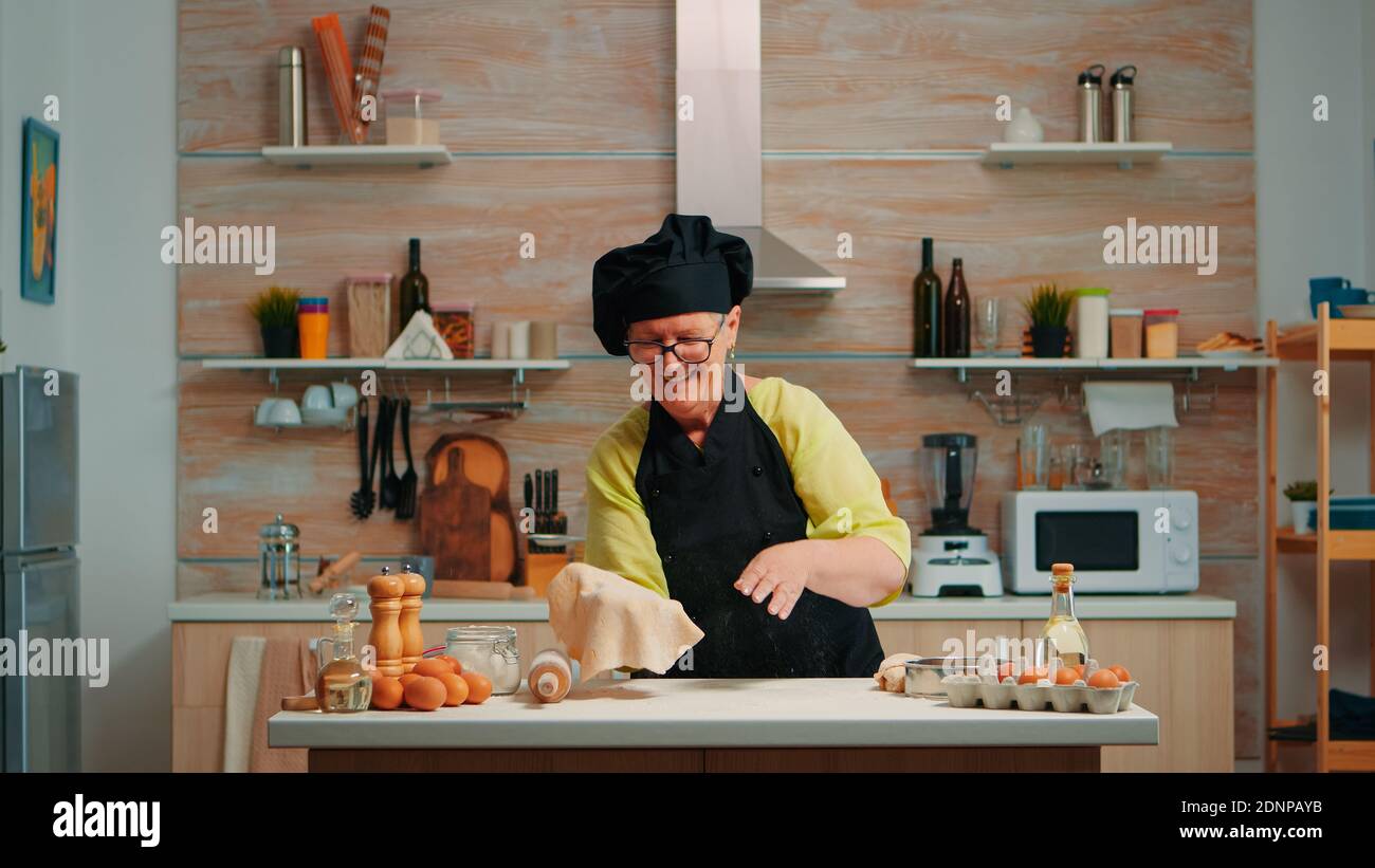 Woman with bonete having fun cooking at home in modern kitchen, making ...