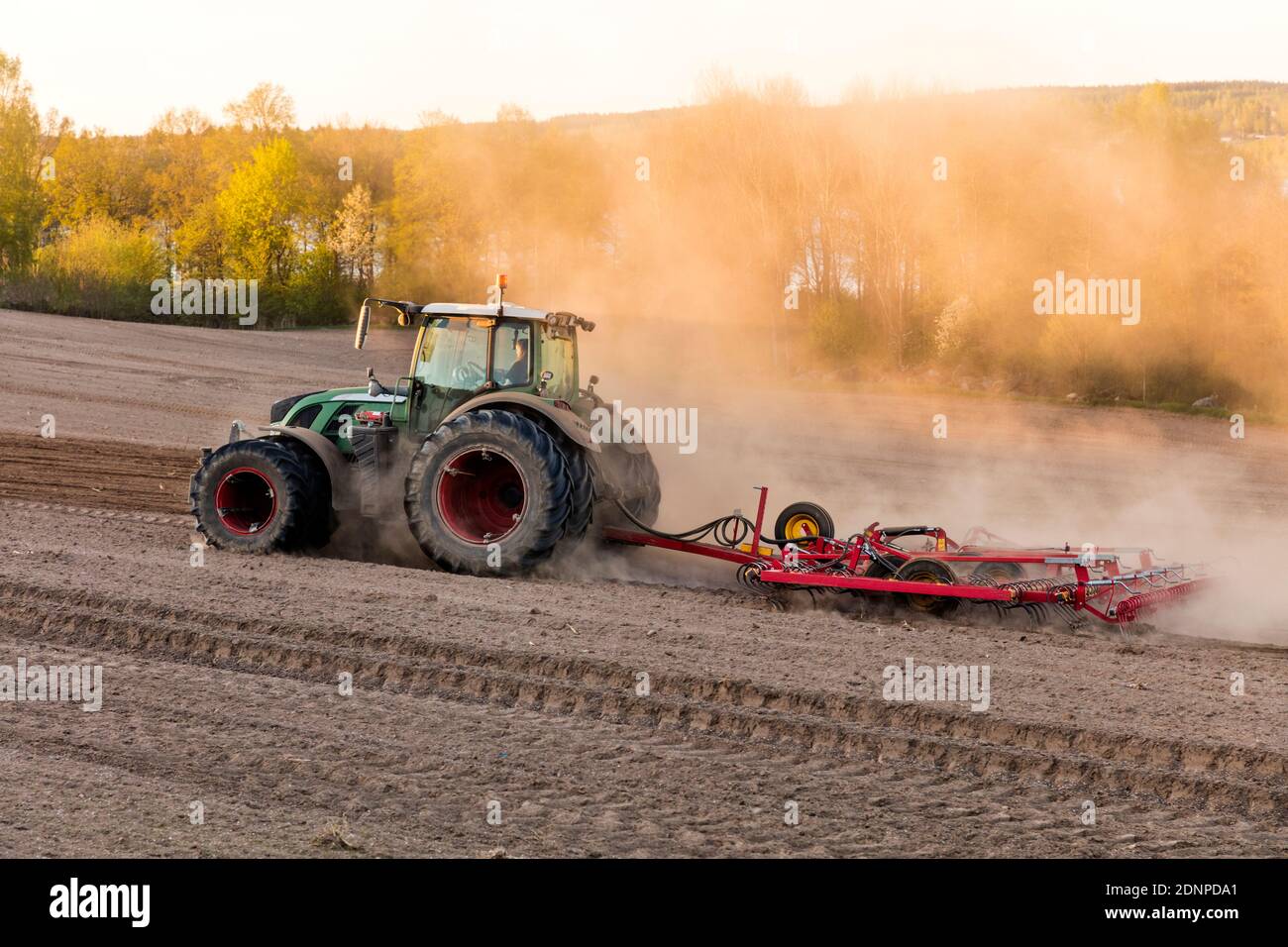 Tractor harrowing field Stock Photo - Alamy