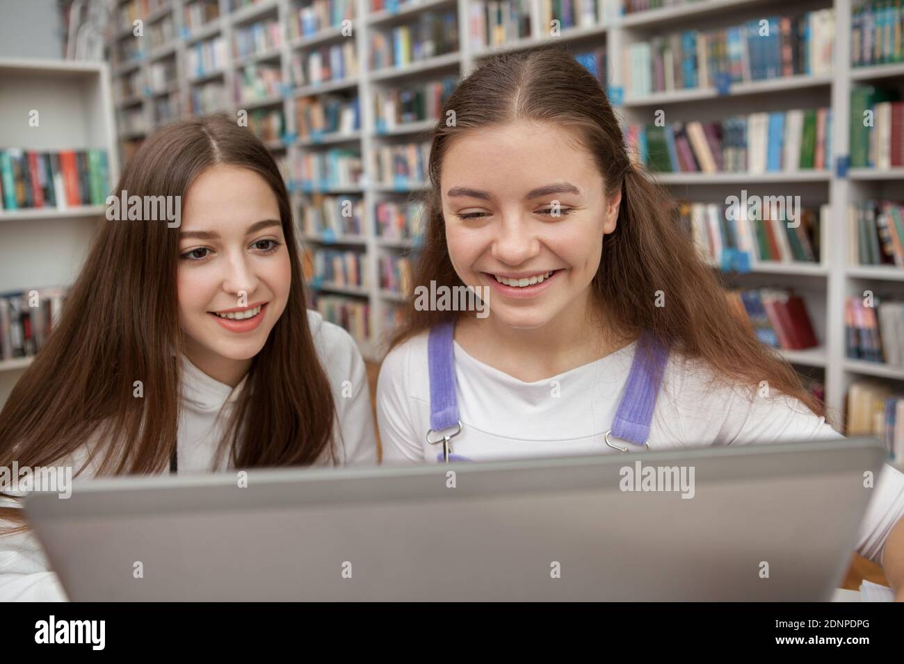 Happy teenage girls laughing while working on a computer together at ...