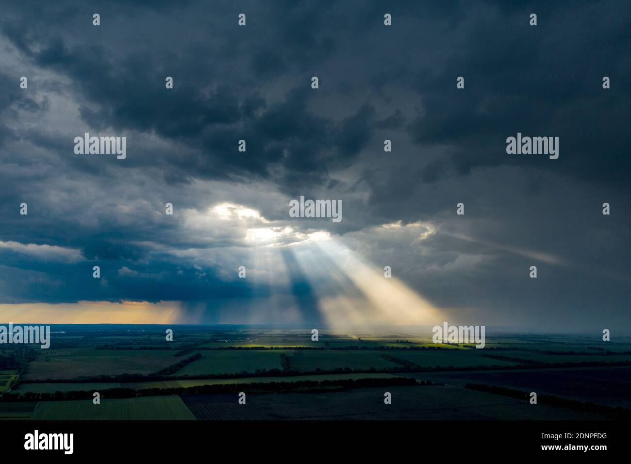 Aerial flying above stunning field under dramatic rain cloud rolling ...