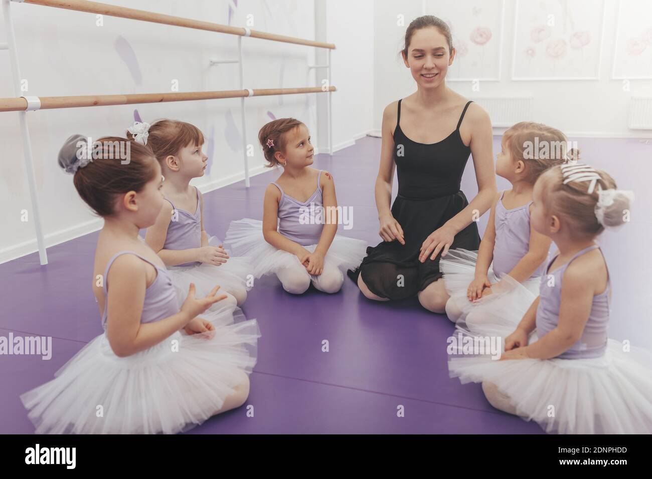 Lovely young ballerina enjoying teaching ballet class to her little ...