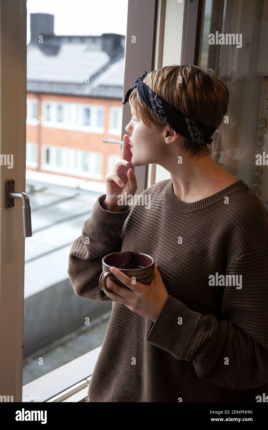 Woman smoking cigarette at window Stock Photo - Alamy