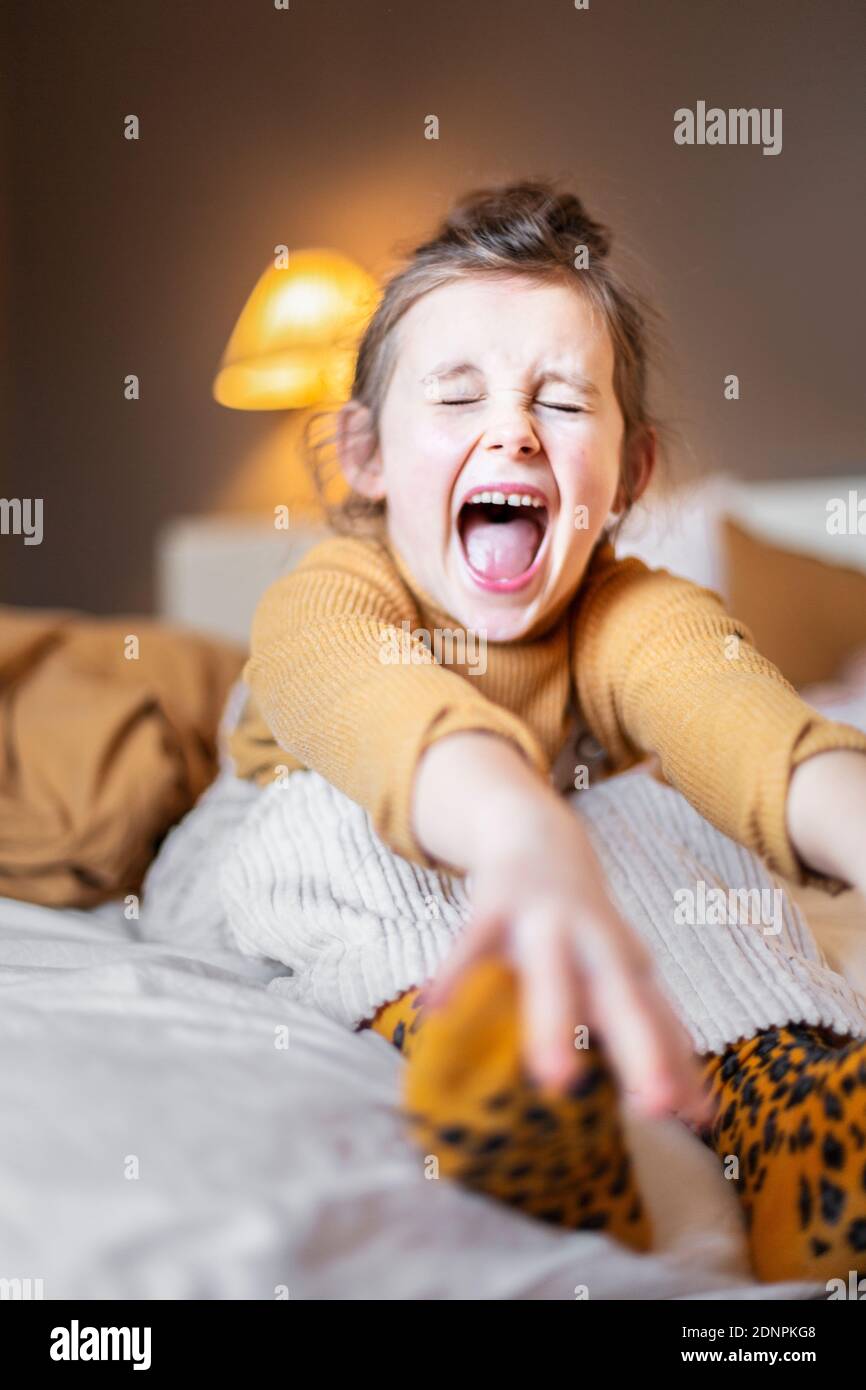 Happy girl sitting on bed Stock Photo - Alamy