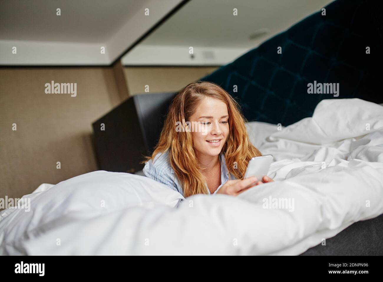 Woman lying on hotel bed with phone hi-res stock photography and images ...