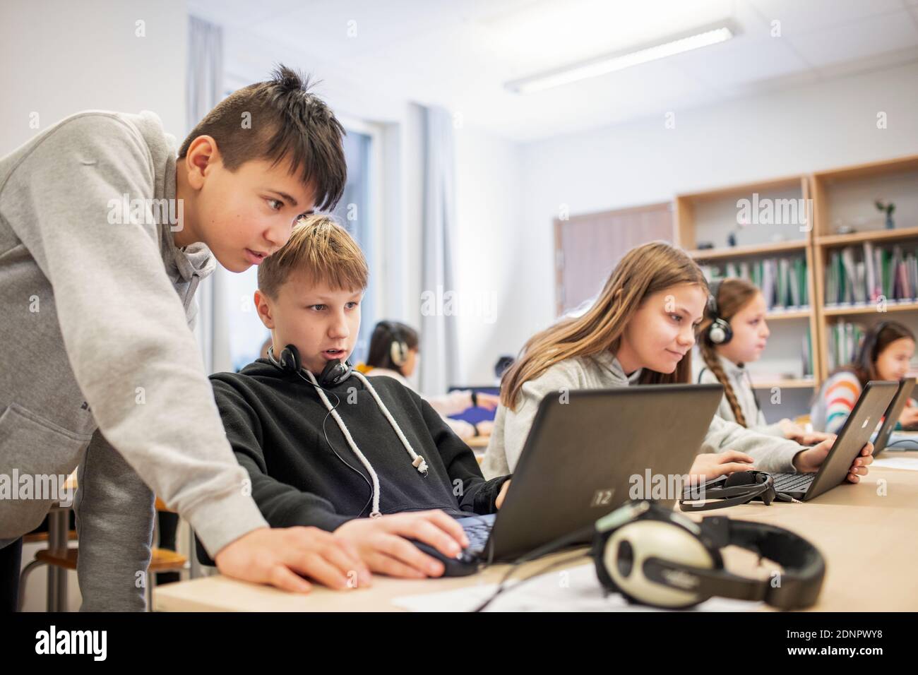 Boys in classroom using laptop Stock Photo - Alamy