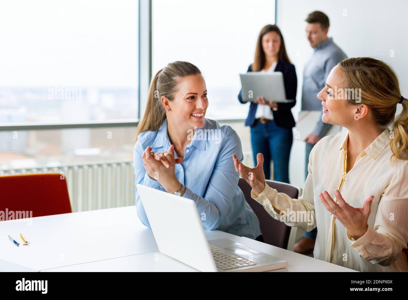 Female coworkers talking at work Stock Photo - Alamy