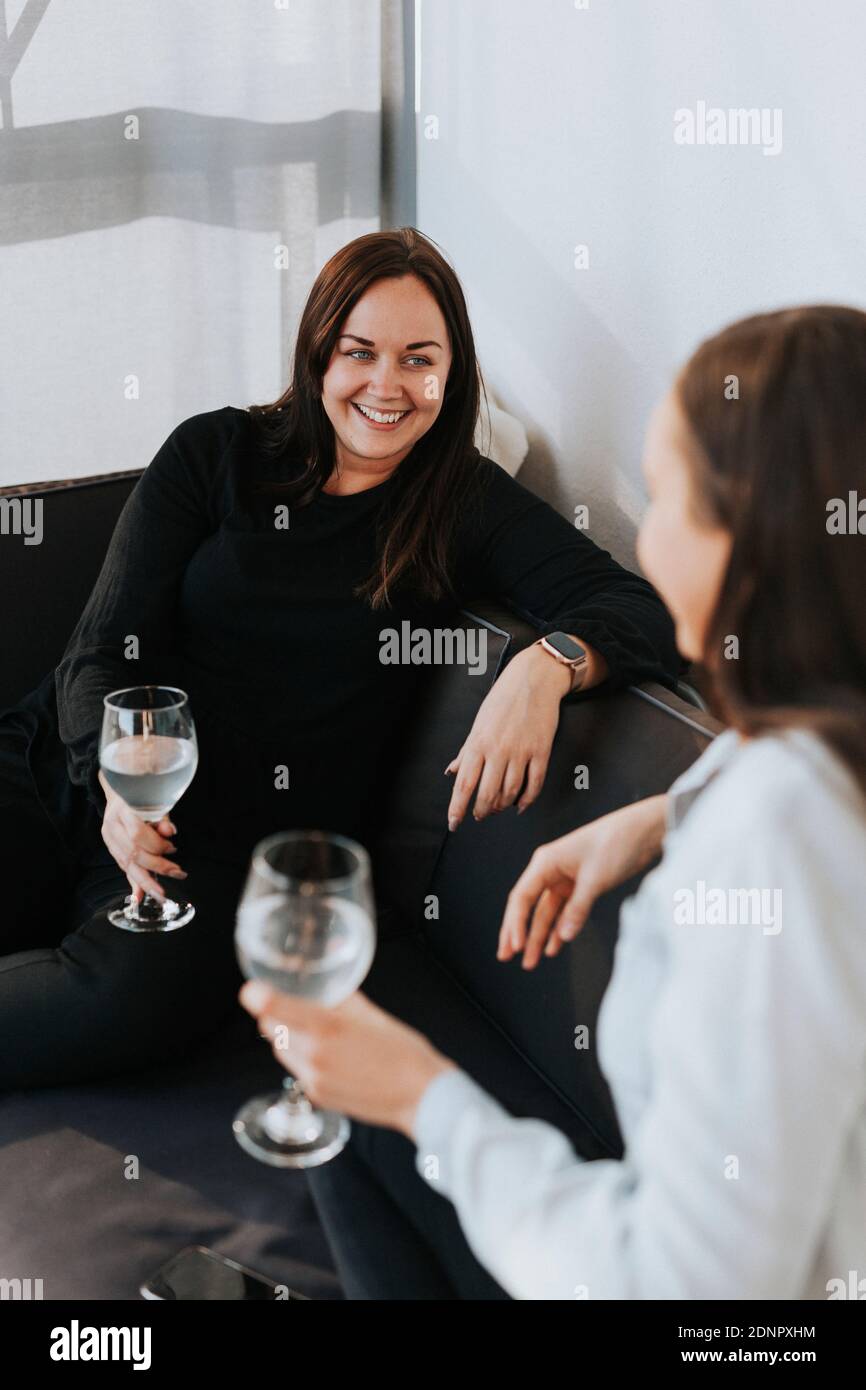 Smiling women talking on sofa Stock Photo - Alamy