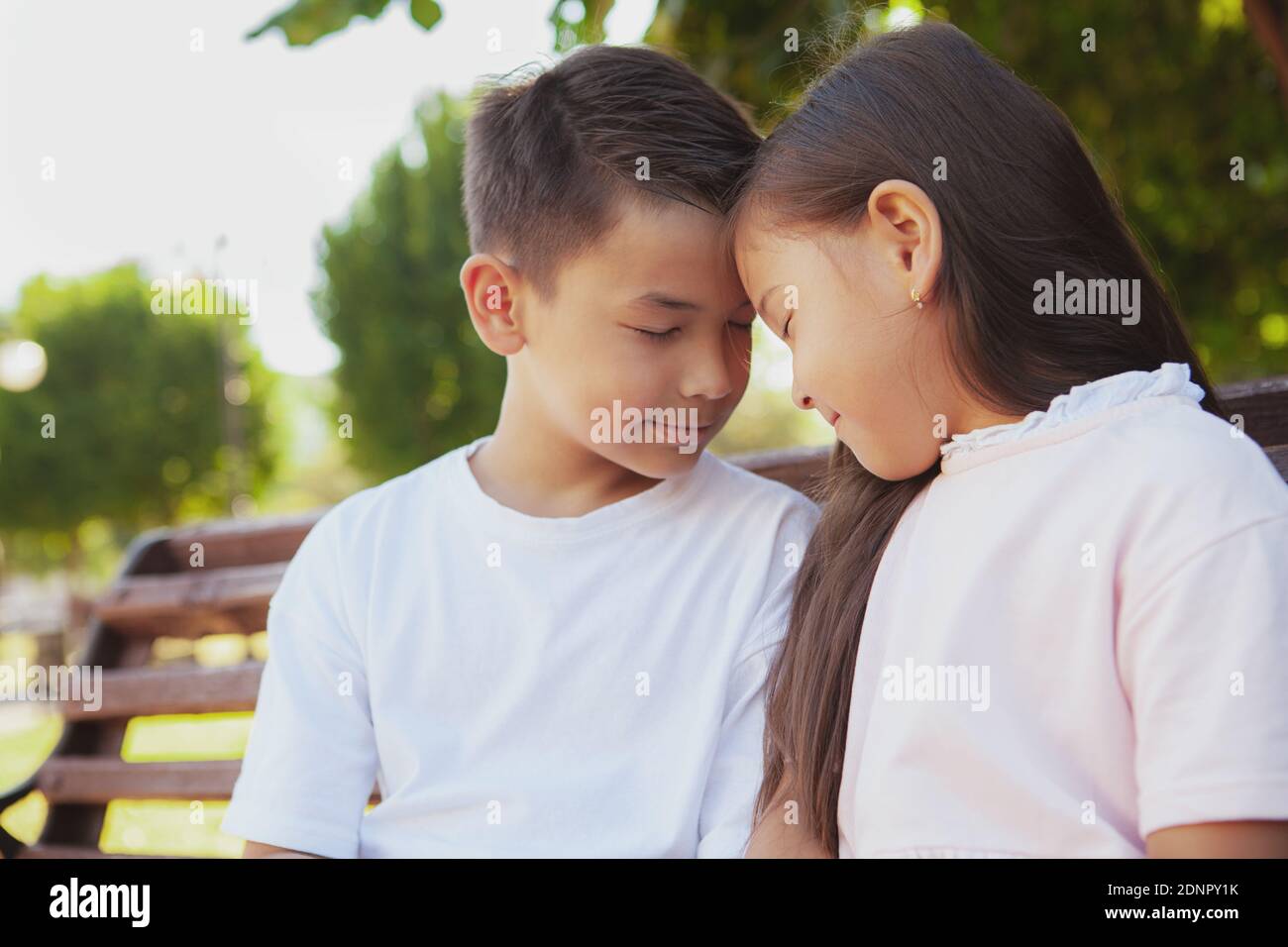 Young lovely boy touching foreheads with his little sister. Adorable ...