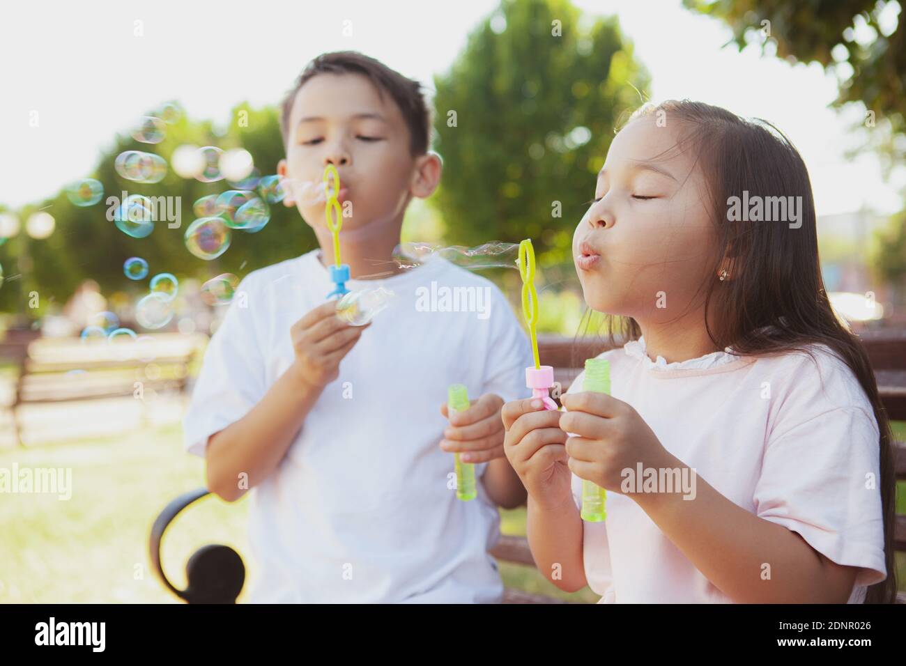Happy cute little kids blowing bubbles outdoors in the park. Lovely ...