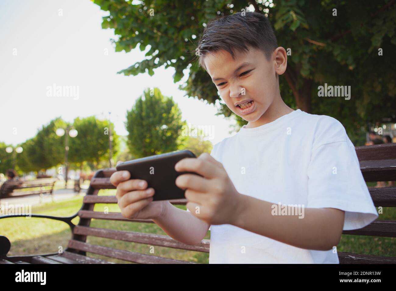 Low angle shot of a young Asian boy looking angry, playing online games ...