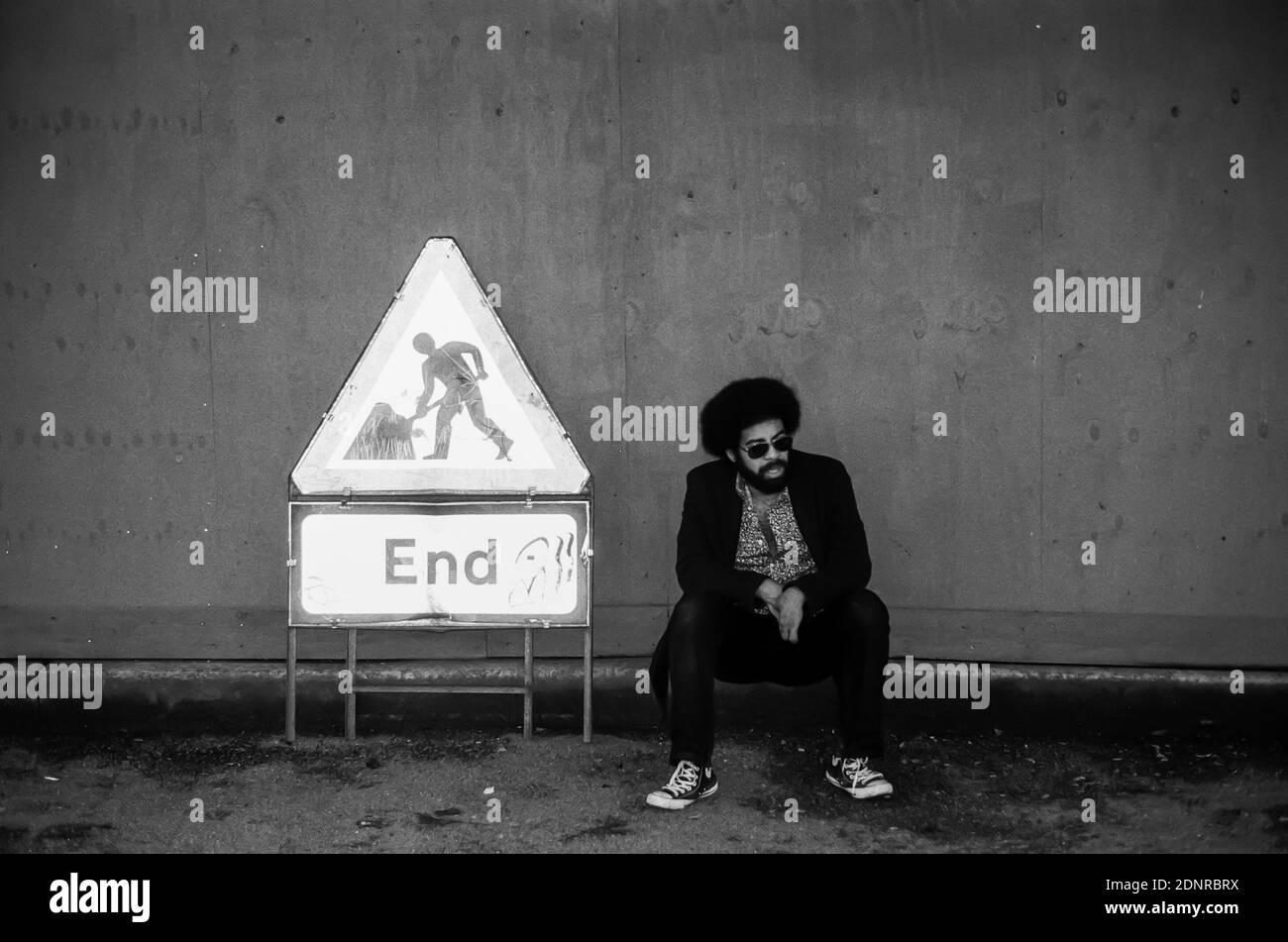 Bearded Man Sitting By Sign Against Wall Stock Photo - Alamy