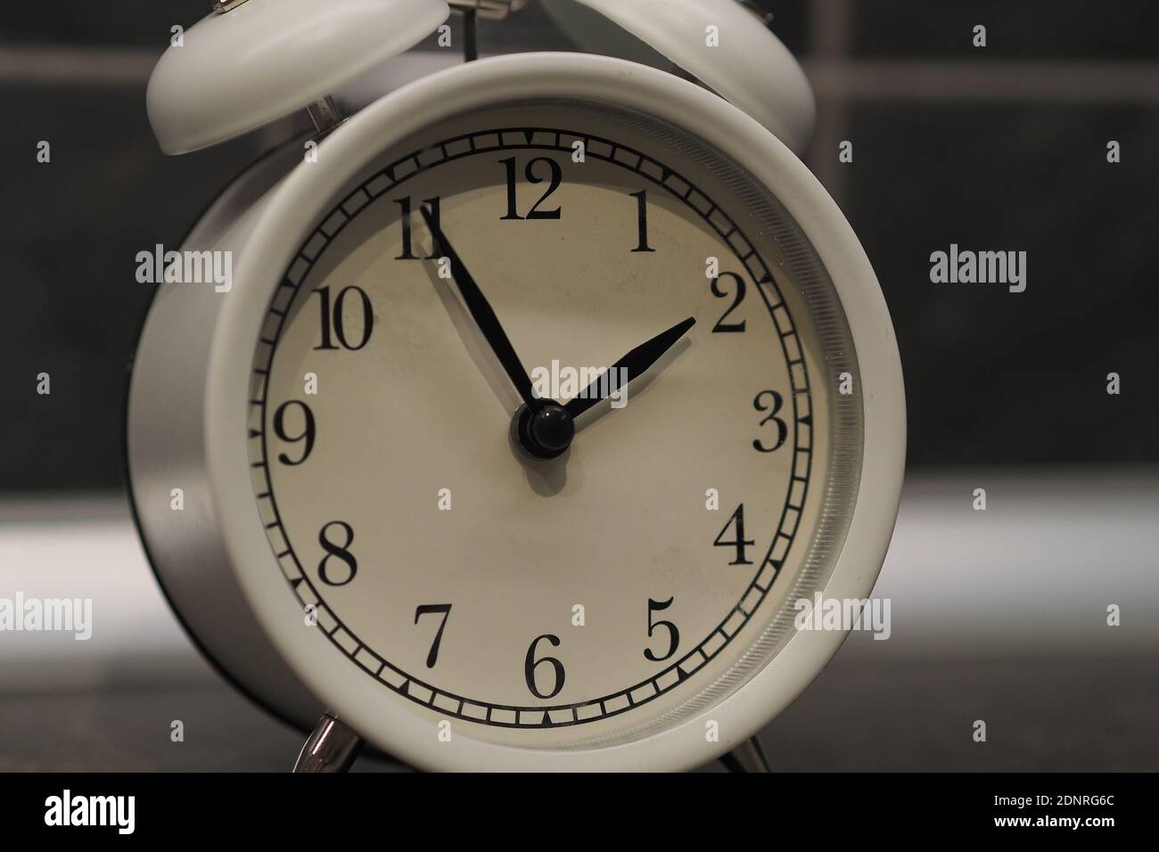 Round clock-alarm white on a gray background, isolated, close-up Stock ...