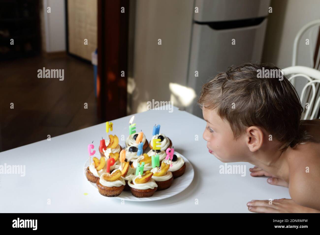 Child blowing out candles on the birthday cake Stock Photo - Alamy