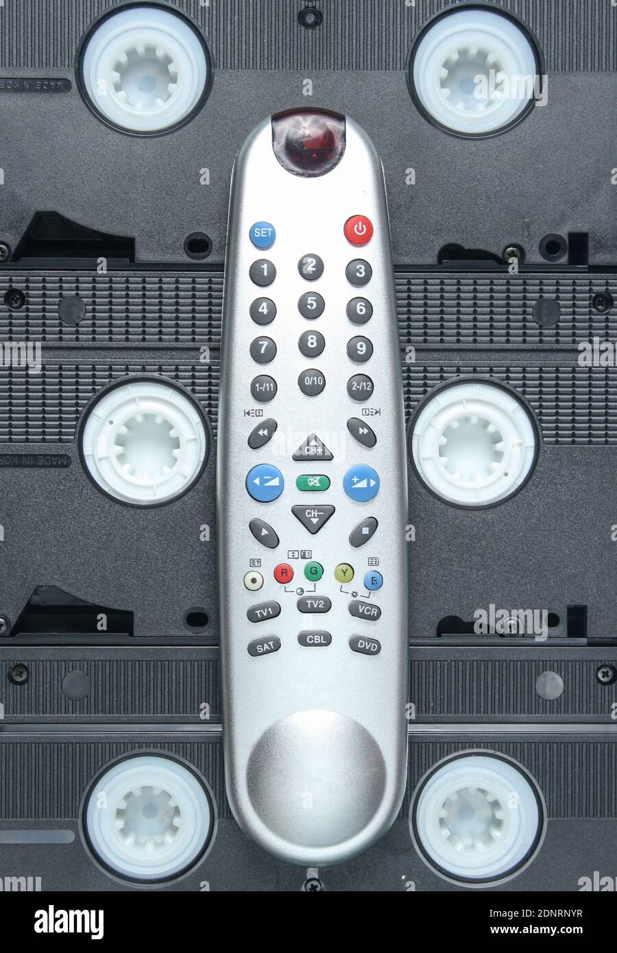 Modern TV remote on background of video cassettes. Top view, minimalism ...
