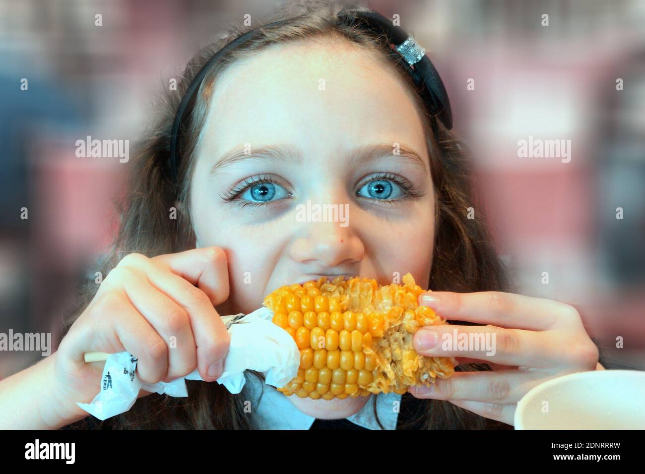 Portrait of a girl eating a corn cob Stock Photo - Alamy