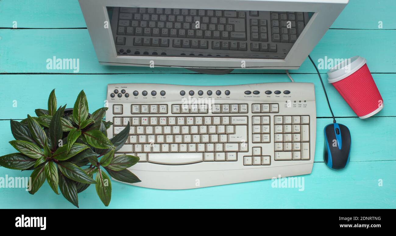 Retro computer on blue wooden table. Monitor, keyboard, pc mouse, pot ...