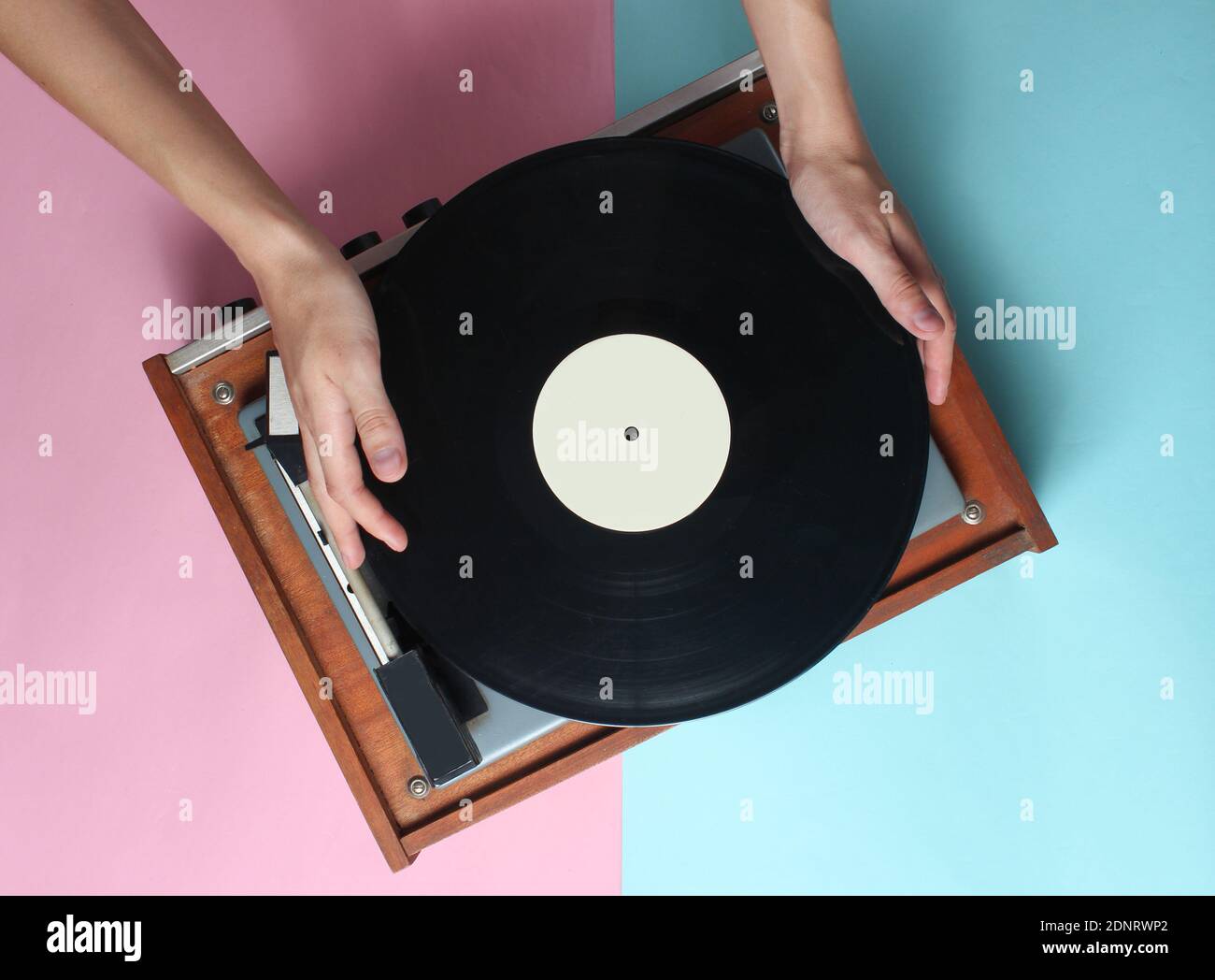 Female hands use retro vinyl player on a blue pink pastel background ...