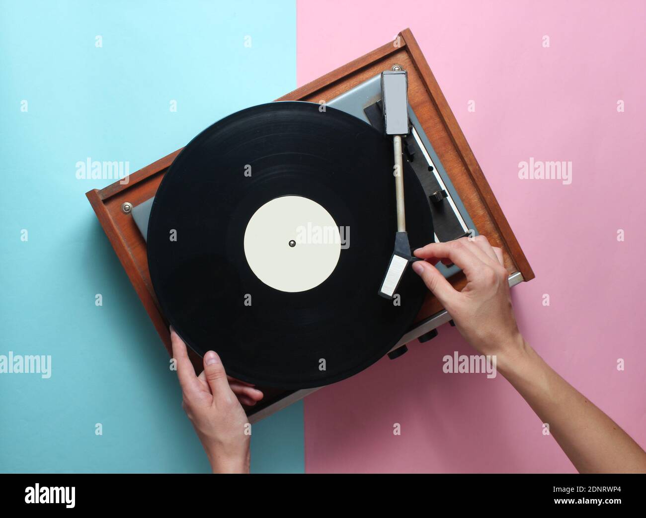 Female hands use retro vinyl player on a blue pink pastel background ...