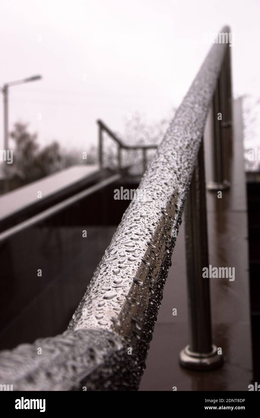 Railing in the rain. Chrome, shiny railing in raindrops under the open ...