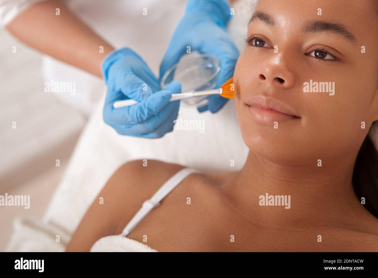 Cropped shot of a lovely young African woman getting facial peeling at ...