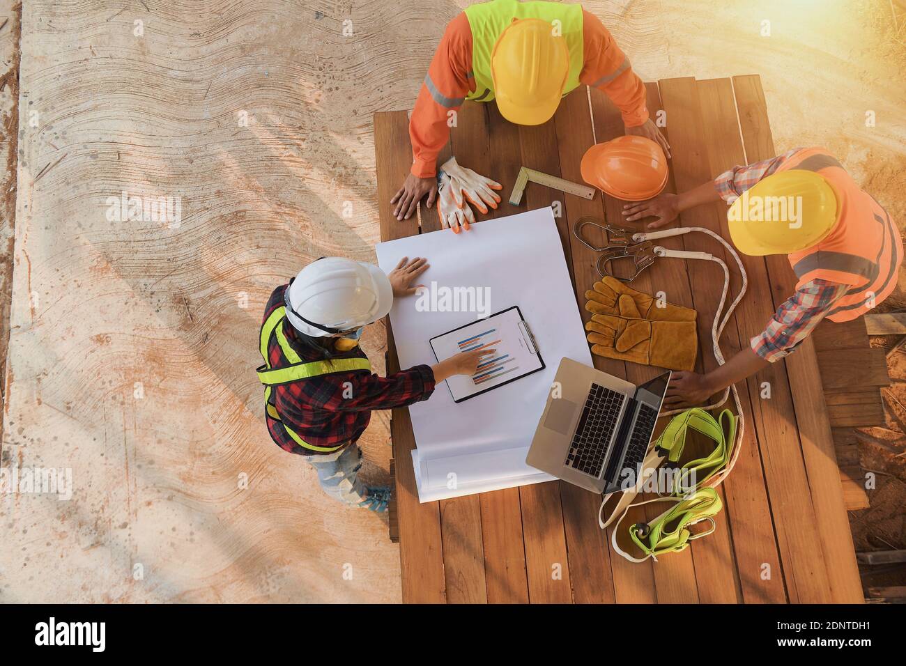 Overhead view of a three construction workers looking at graphs ...