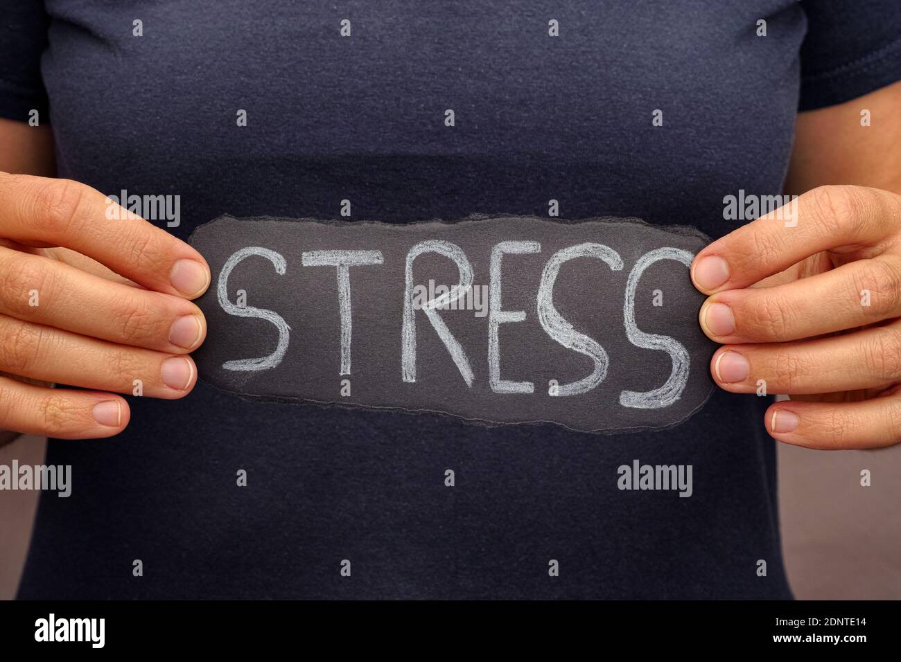 Woman holding the word Stress written on a black paper. Close up Stock ...