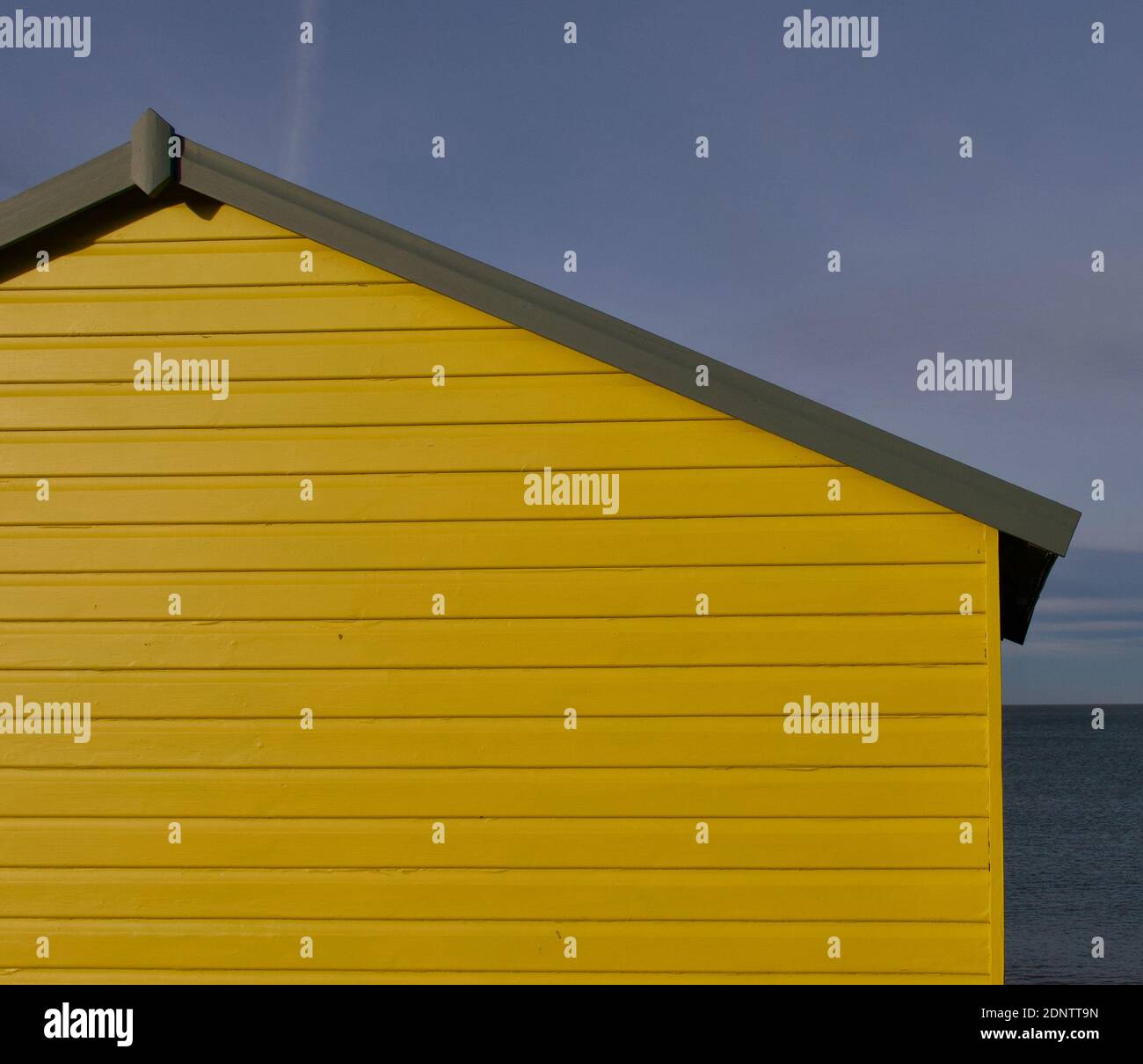 Bright yellow beach shack with copy space with sea visible to side ...