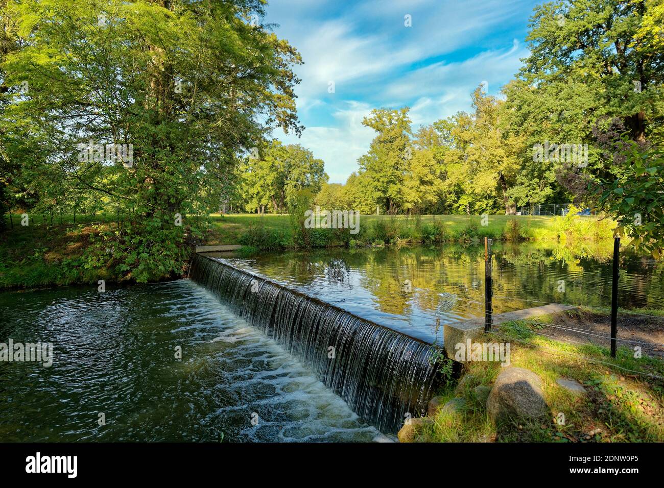 River flowing over a small weir in a park in summer, Germany Stock ...