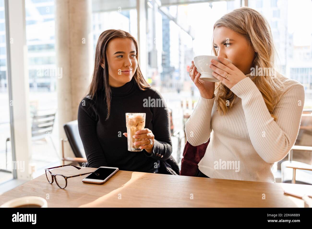 Smiling Women Talking and Drinking Coffee At Modern Cafe in City Stock ...