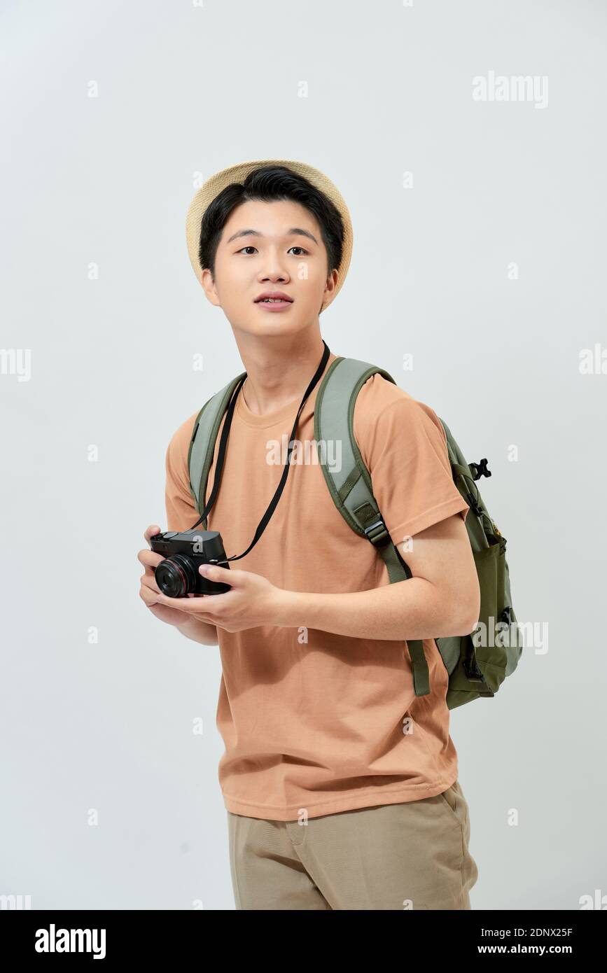 Portrait of cheerful young Asian tourist man holding digital camera and ...