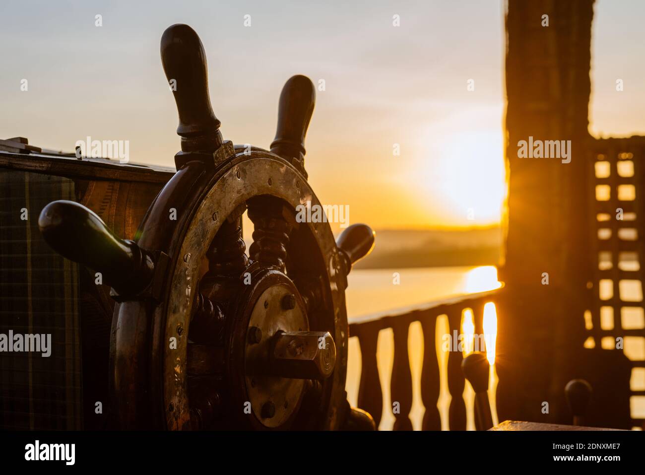 Wooden Helm or steering wheel of a shipping vessel with a sunrise in ...