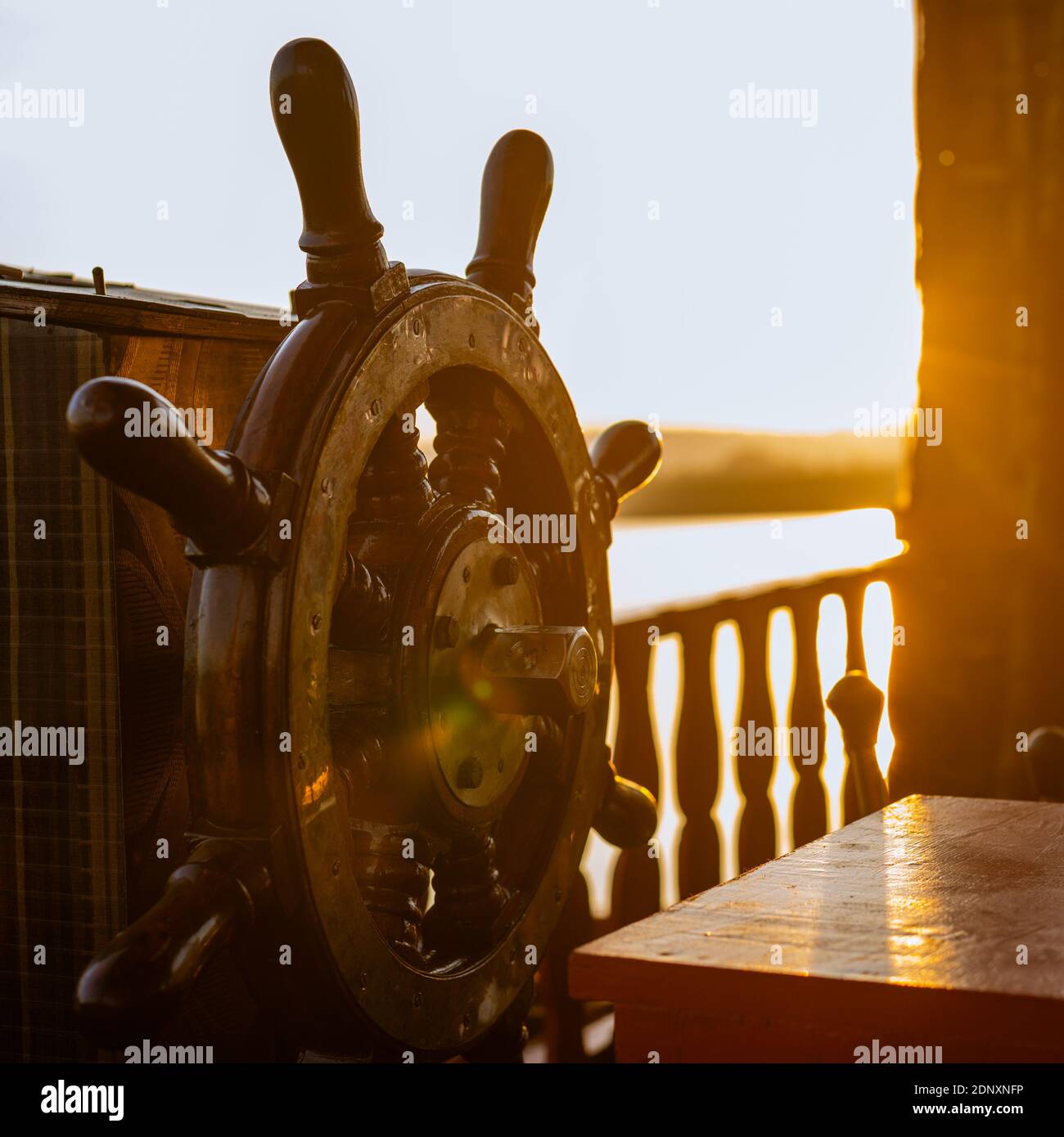 Wooden Helm or steering wheel of a shipping vessel with a sunrise in ...