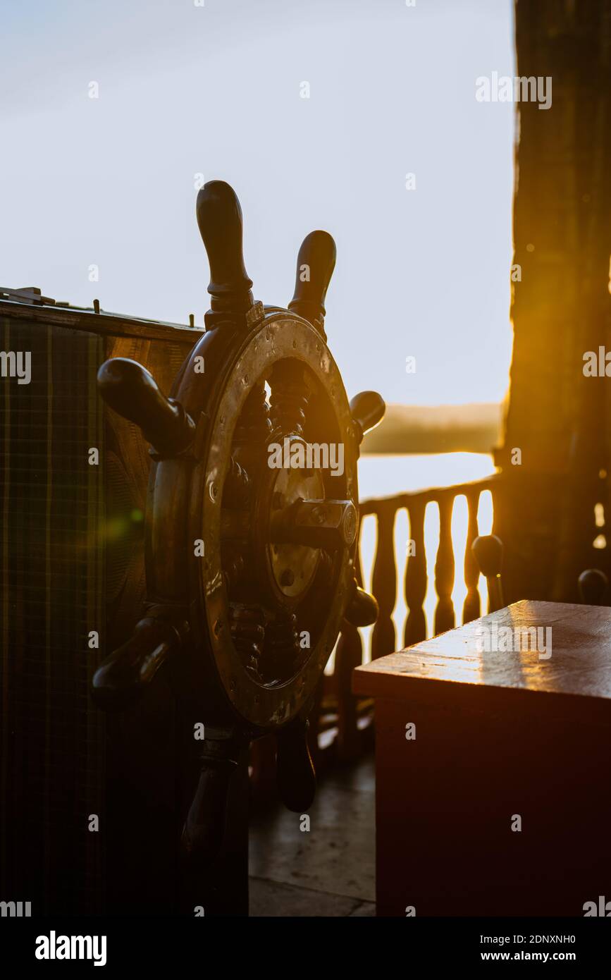 Wooden Helm or steering wheel of a shipping vessel with a sunrise in ...