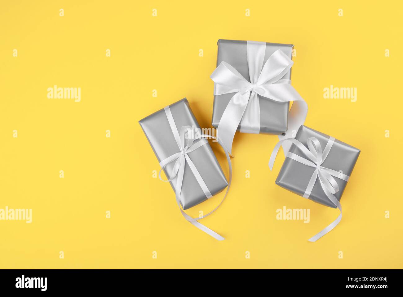Trendy attractive minimalistic gray gift on the yellow background ...
